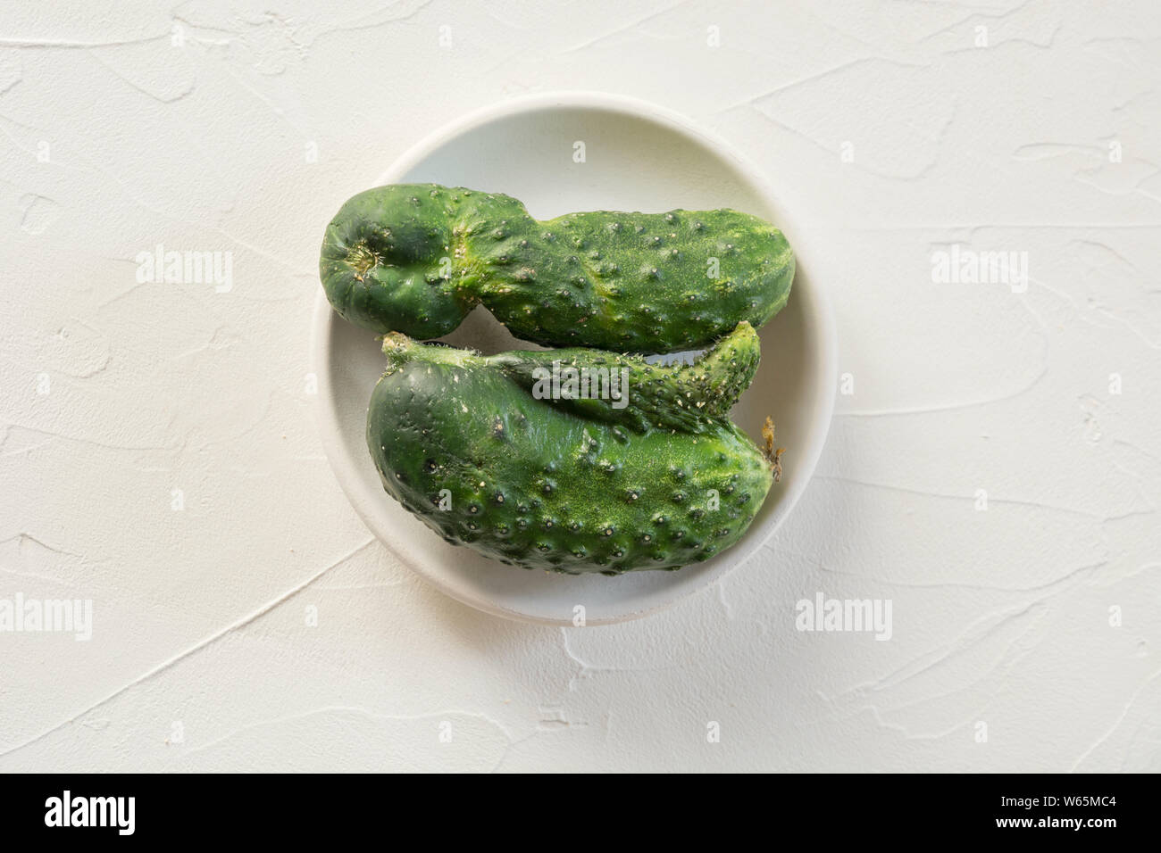 Ugly organic abnormal two cucumber on white concrete table. Concept ...