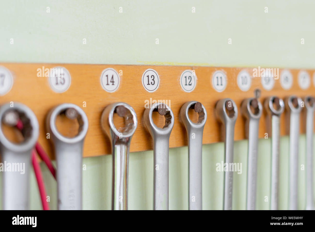 collection of spanners hanging on the wall on a wooden holder Stock ...