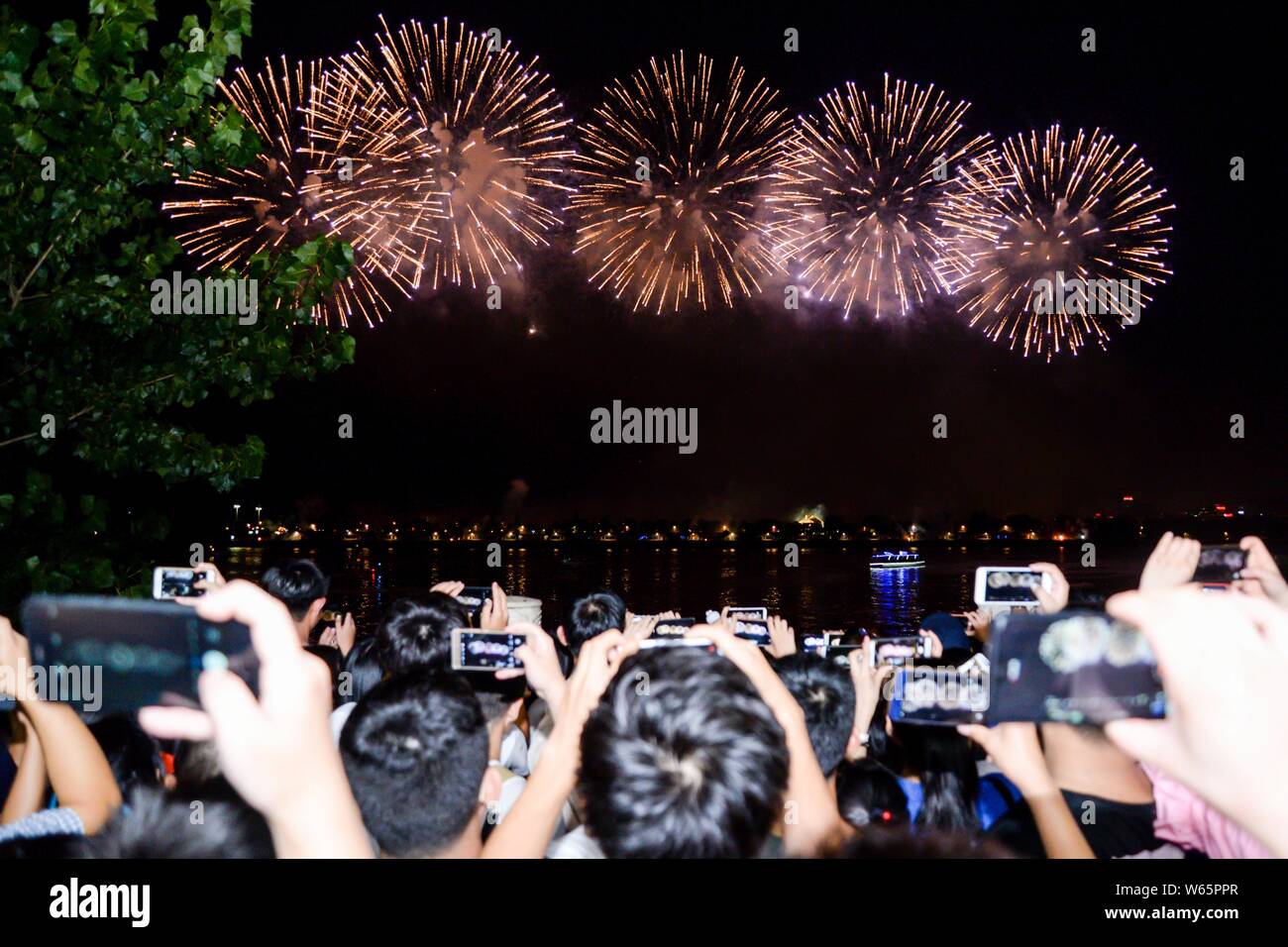 Tourists watch fireworks exploding in the sky over the Xiangjiang River ...