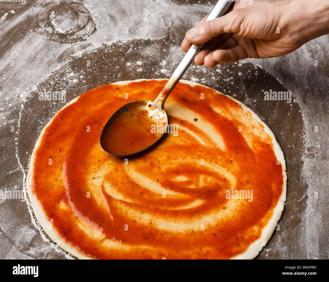 Spreading tomato sause on pizza base, closeup Stock Photo - Alamy