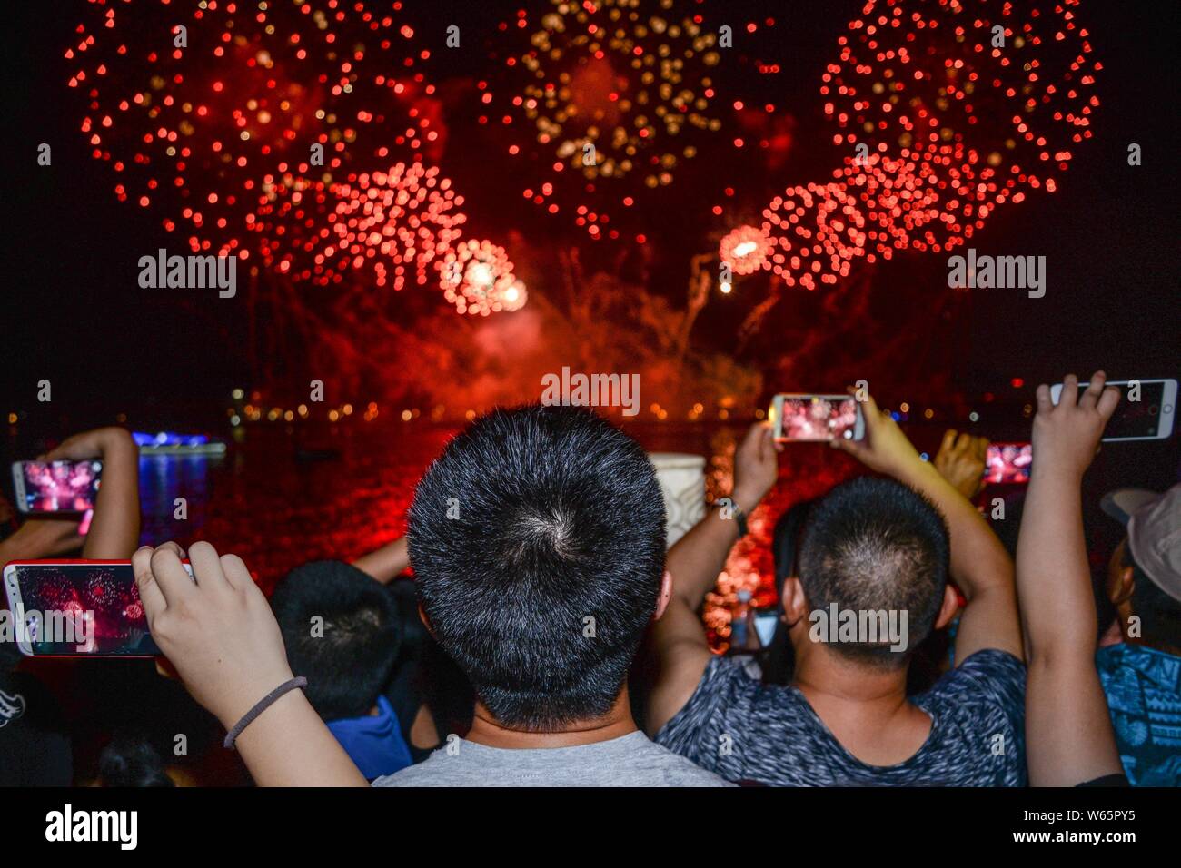 Tourists watch fireworks exploding in the sky over the Xiangjiang River ...