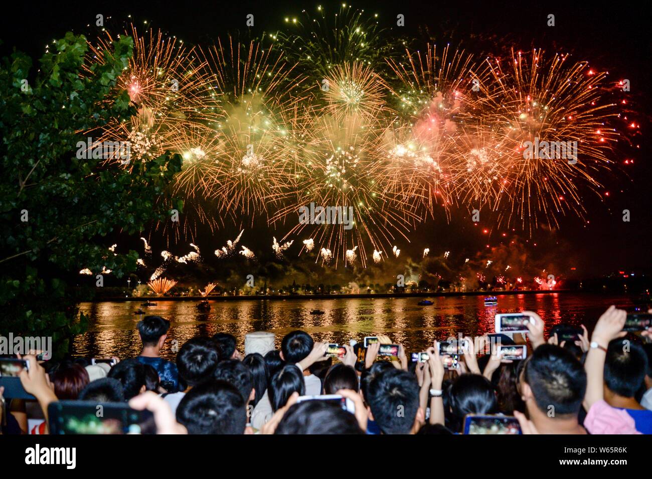Tourists watch fireworks exploding in the sky over the Xiangjiang River ...