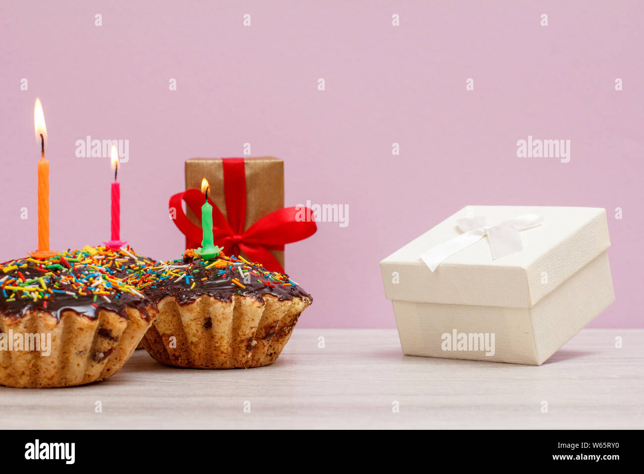 Gift boxes and three tasty birthday muffins with chocolate glaze and ...