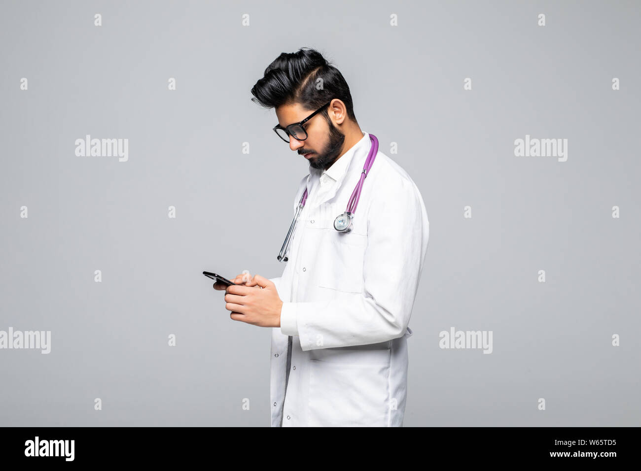 Side-view of indian male doctor looking at smartphone screen and ...