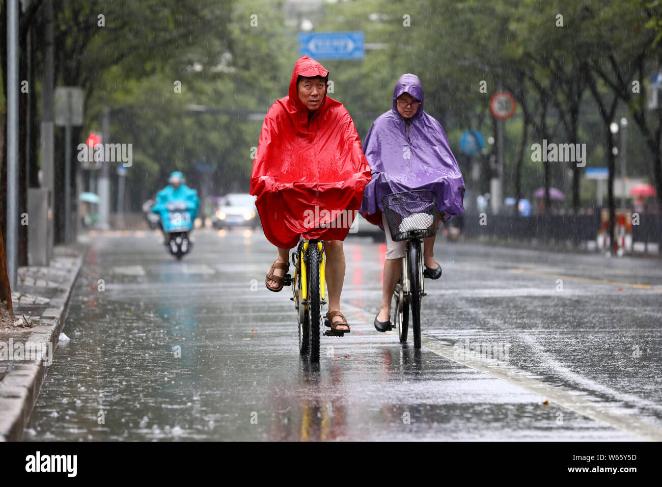 Cyclists wear raincoats as they brave strong wind and heavy rain caused ...
