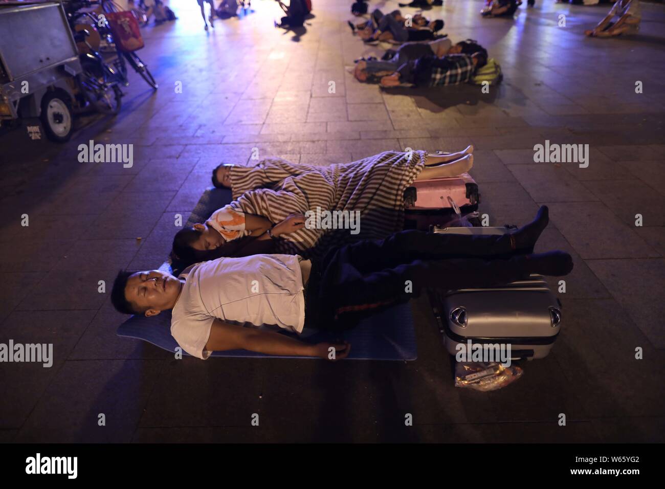 Chinese passengers sleep and wait for their trains at the square of ...