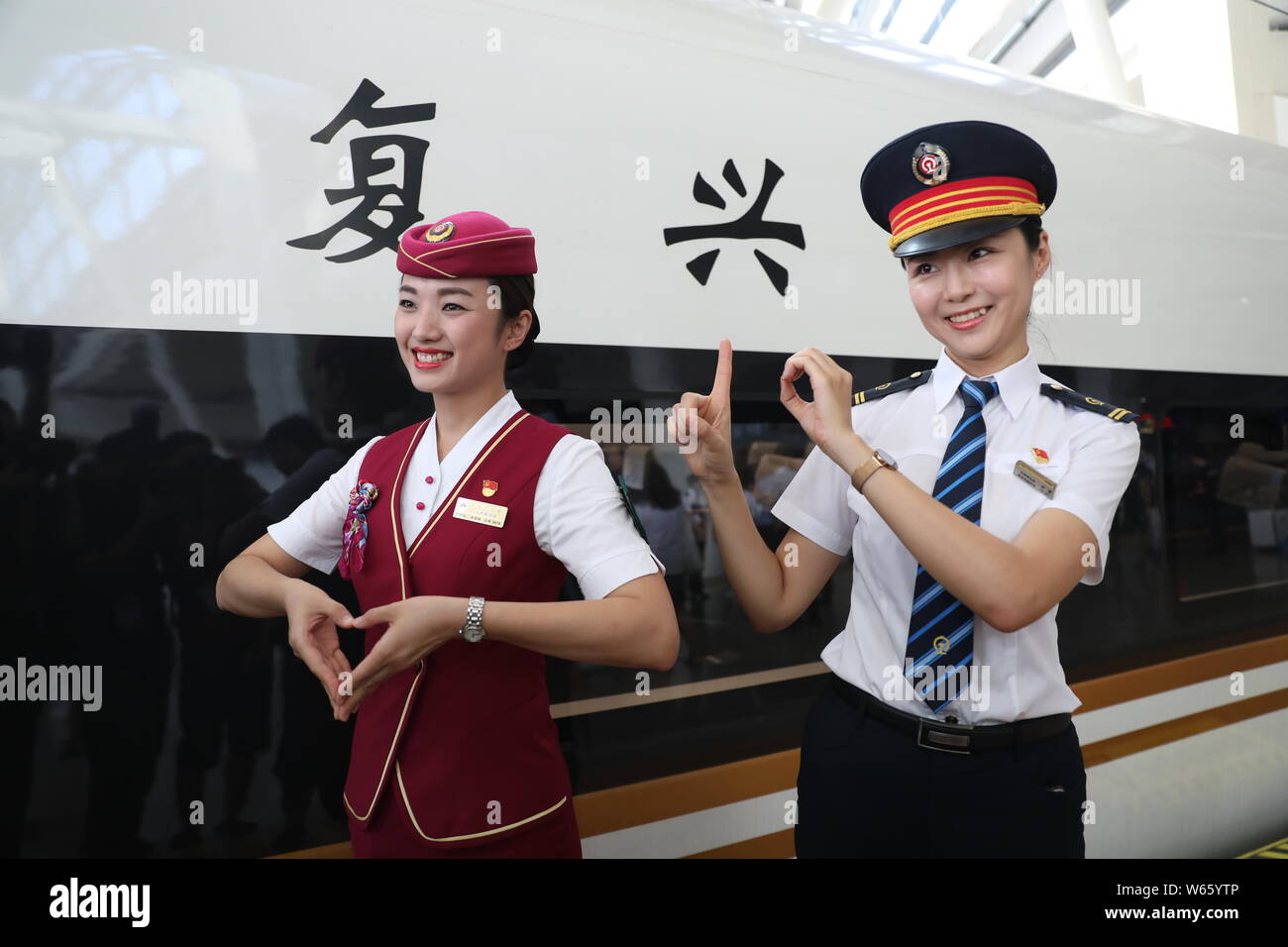 Chinese train attendants pose in front of a "Fuxing" high-speed bullet ...