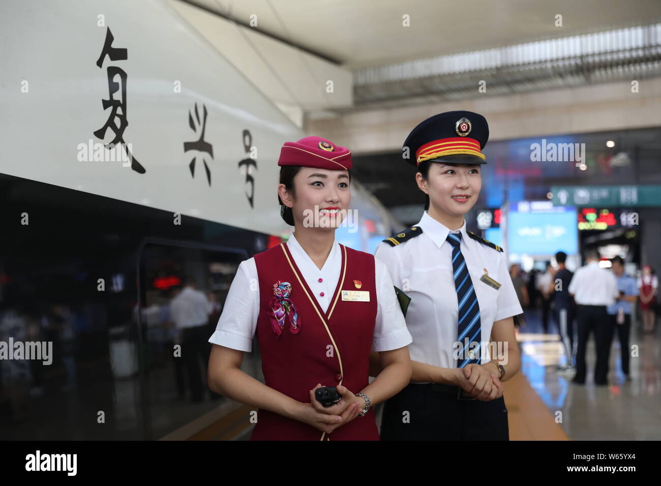 Chinese train attendants pose in front of a "Fuxing" high-speed bullet ...