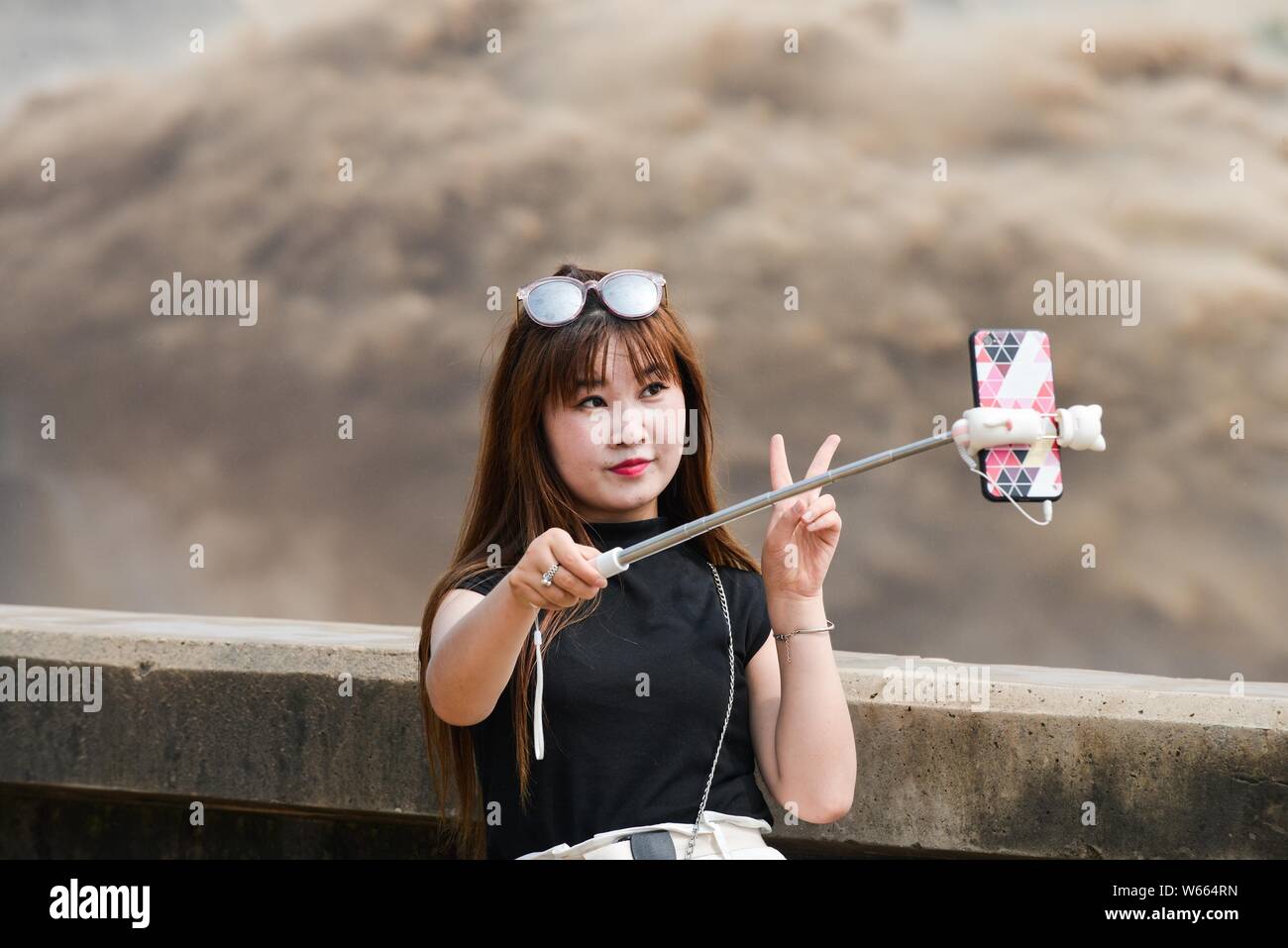 A visitor poses with water gushing out from the Xiaolangdi Dam during a ...