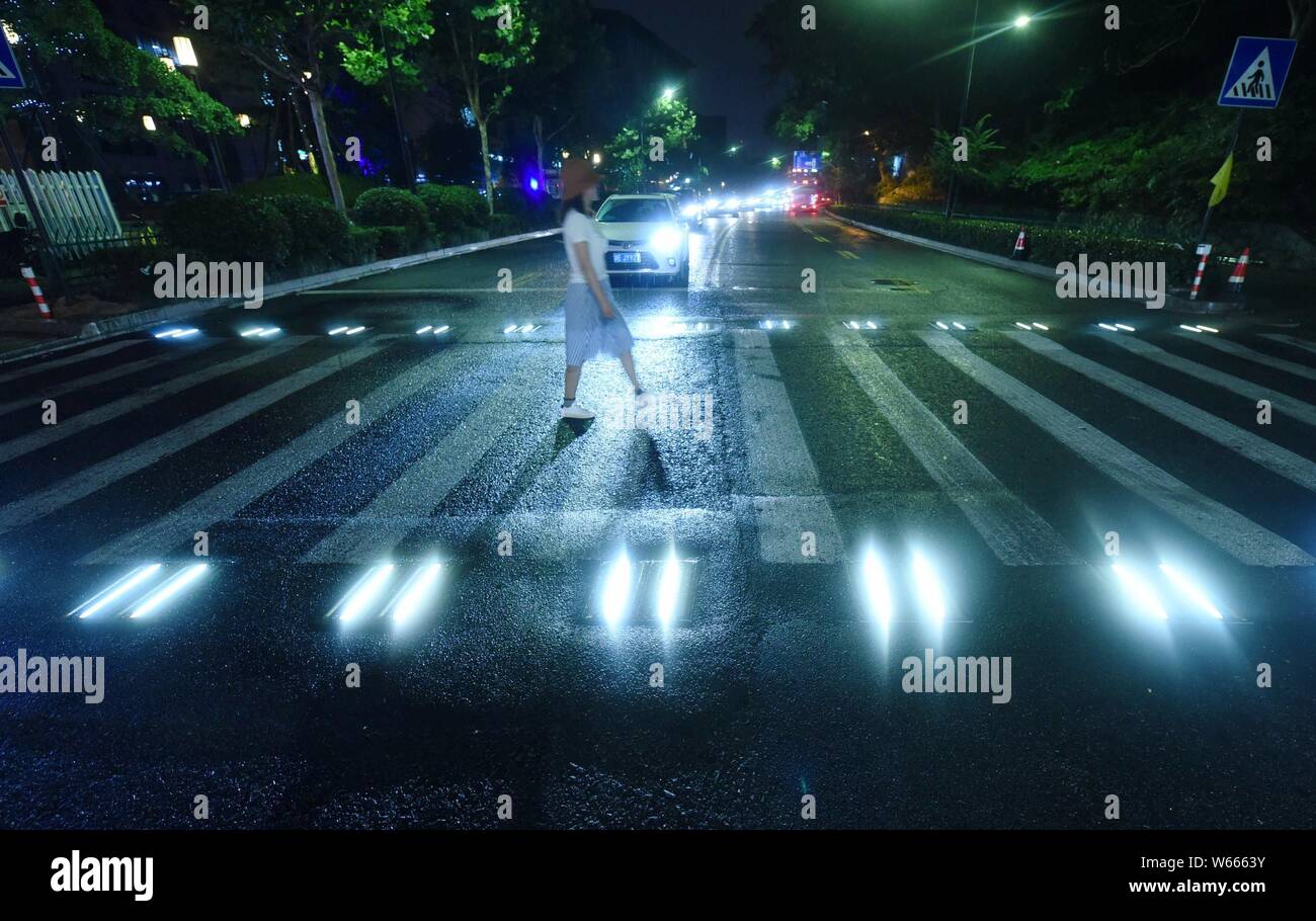A pedestrian walks on an intelligent zebra crossing as the lights ...