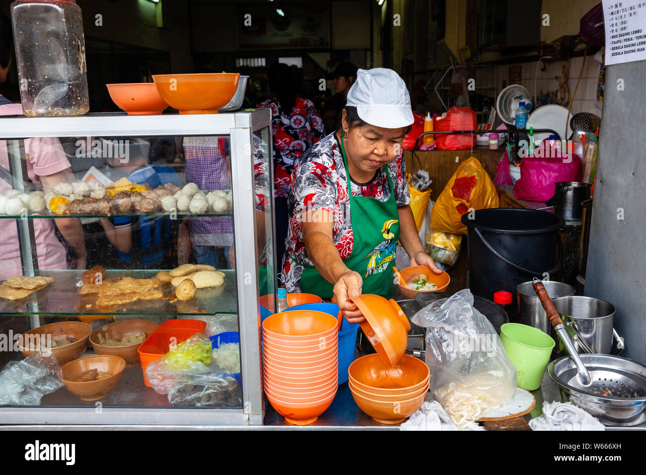 IPOH, MALAYSIA - DECEMBER 11: Woman serves up noodles for clients on a ...