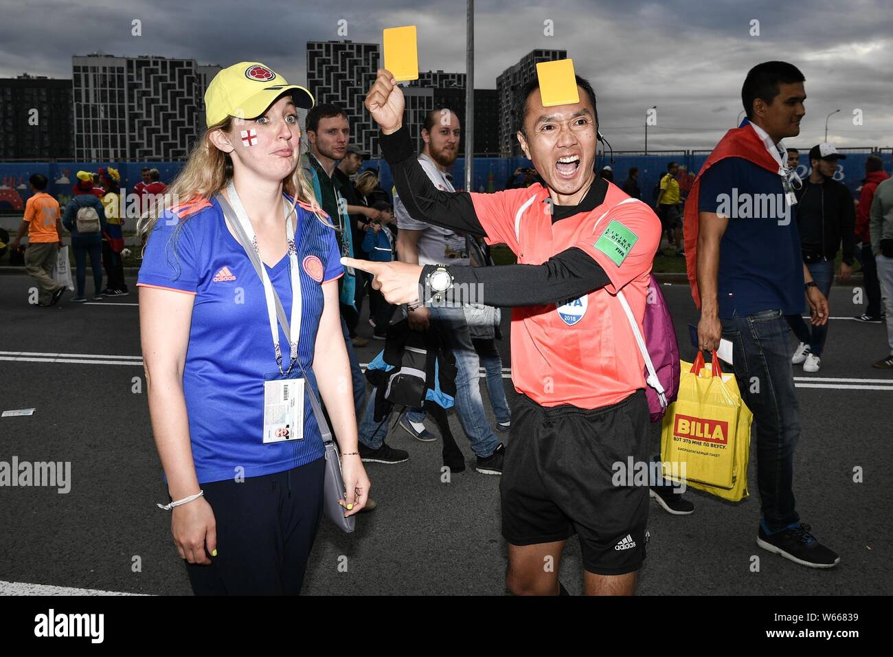 A Japanese fan who cosplays a referee holding up a yellow card poses ...