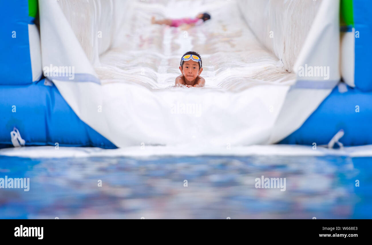 A tourist plays on Asia's longest water slide at Jingzhihu Resort in ...
