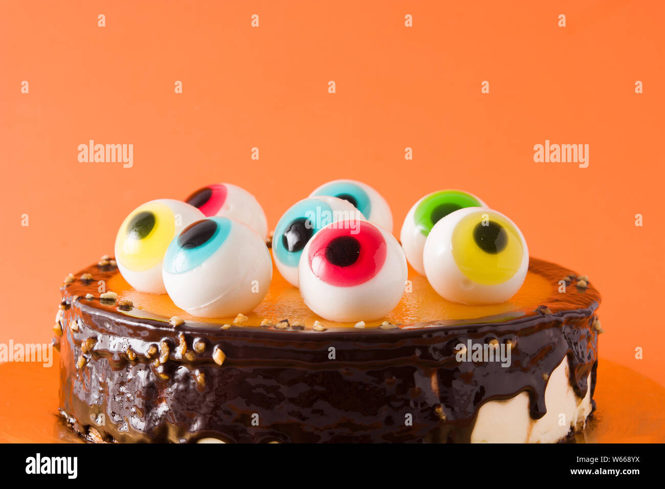 Halloween cake with candy eyes decoration on orange background Stock ...
