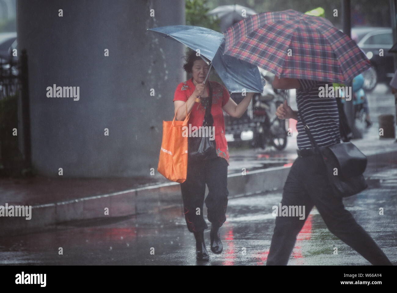 Pedestrians brave heavy downpour caused by Typhoon Ampil, the tenth ...
