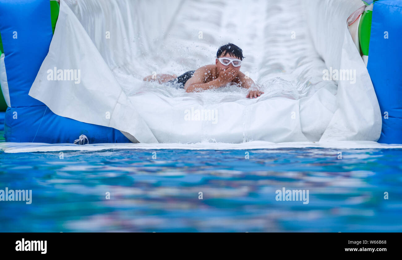 A tourist plays on Asia's longest water slide at Jingzhihu Resort in ...