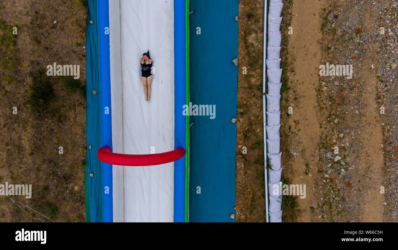 A tourist plays on Asia's longest water slide at Jingzhihu Resort in ...