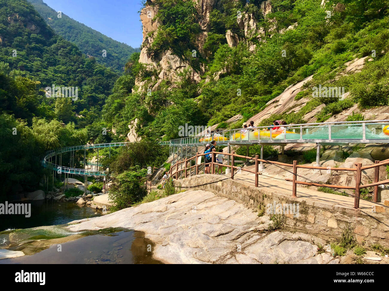 Tourists have fun on the 2.3-kilometer-long glass-bottomed waterslide ...