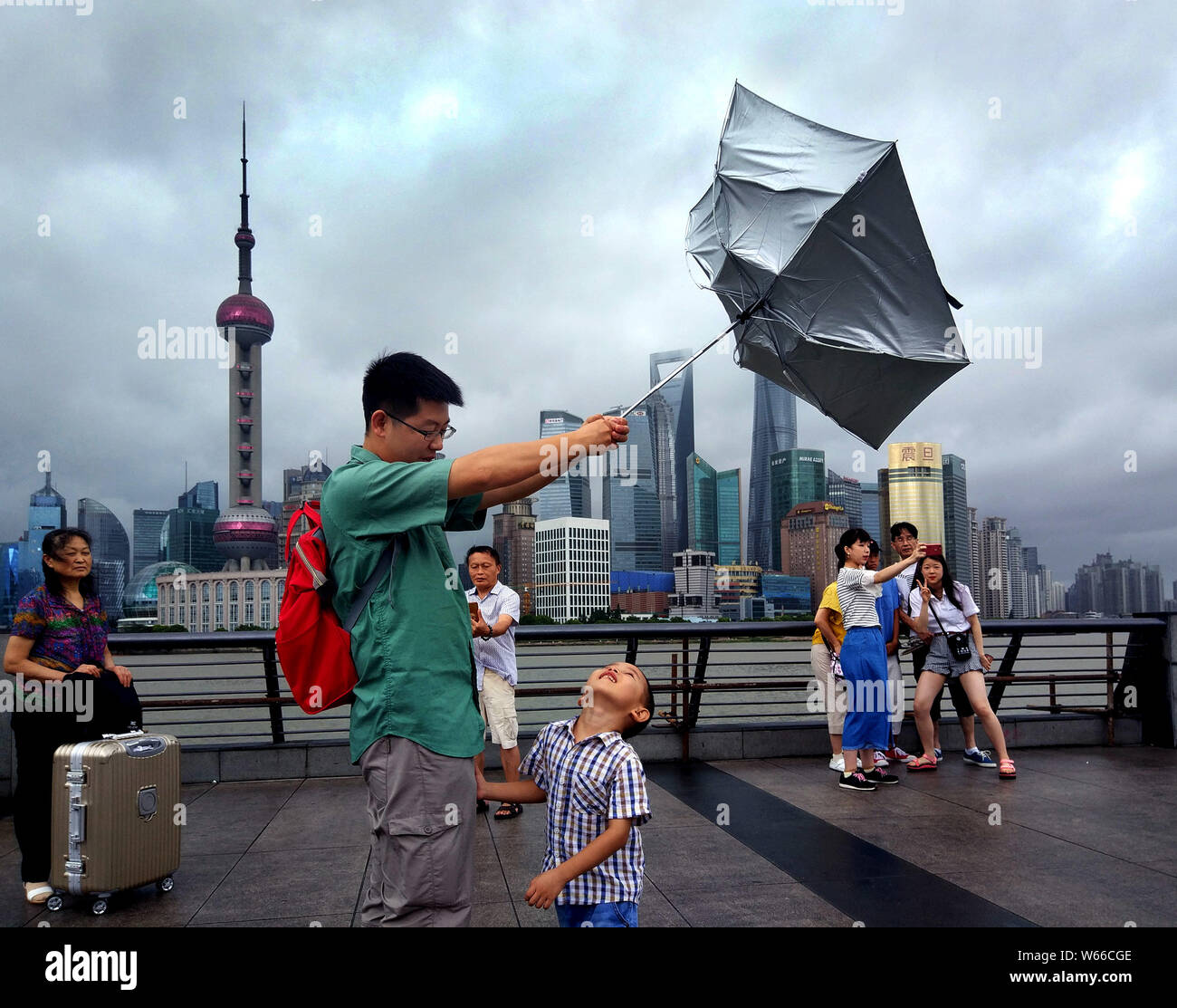 A tourist shielding himself with an umbrella braves strong wind and ...