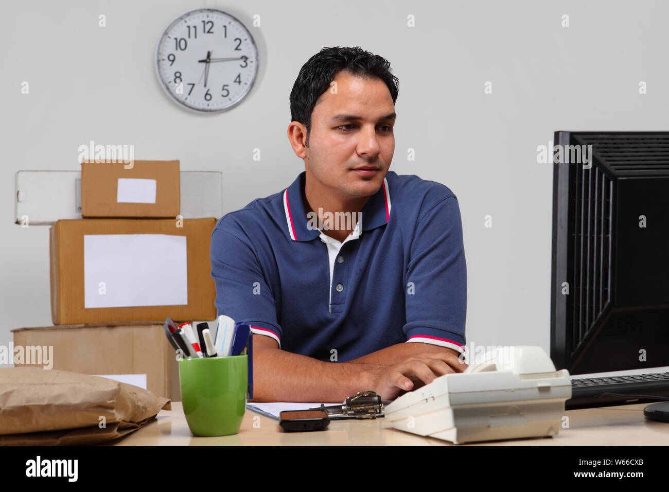 Delivery man working on a desktop pc Stock Photo - Alamy