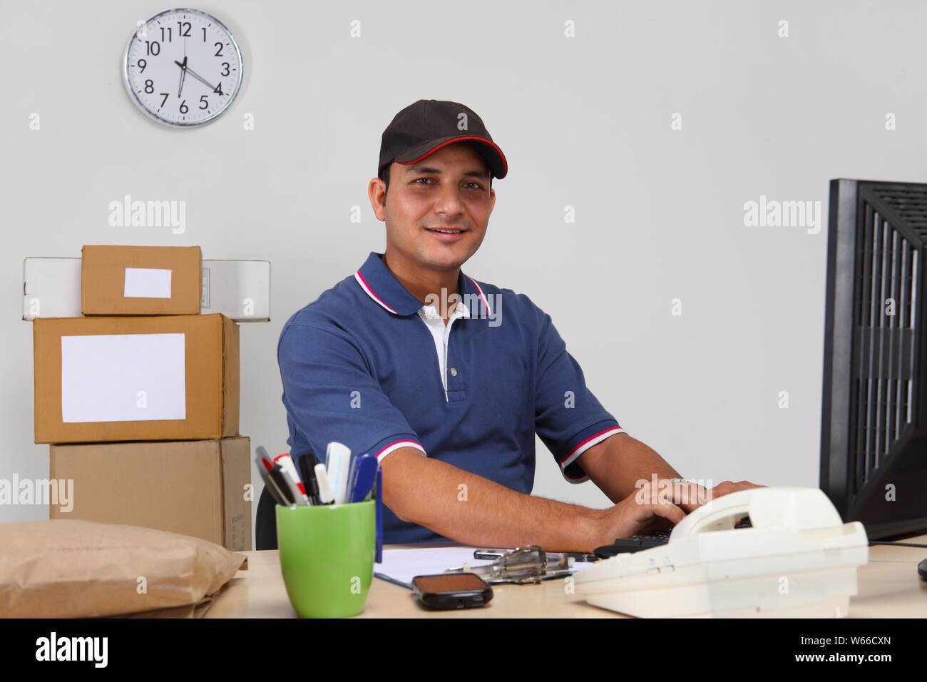Delivery man working on a desktop pc Stock Photo - Alamy