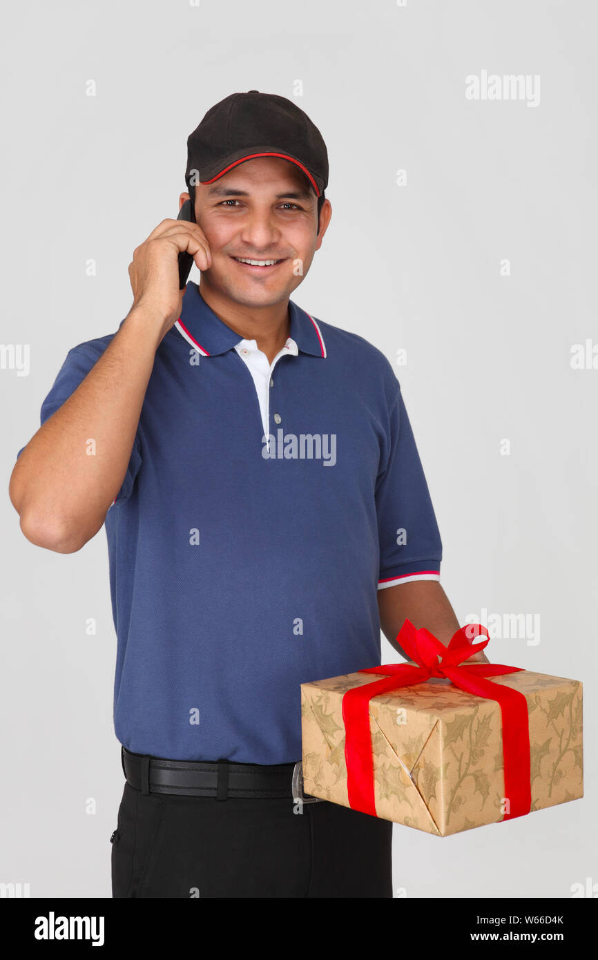 Delivery man talking on mobile phone and delivering parcel Stock Photo ...