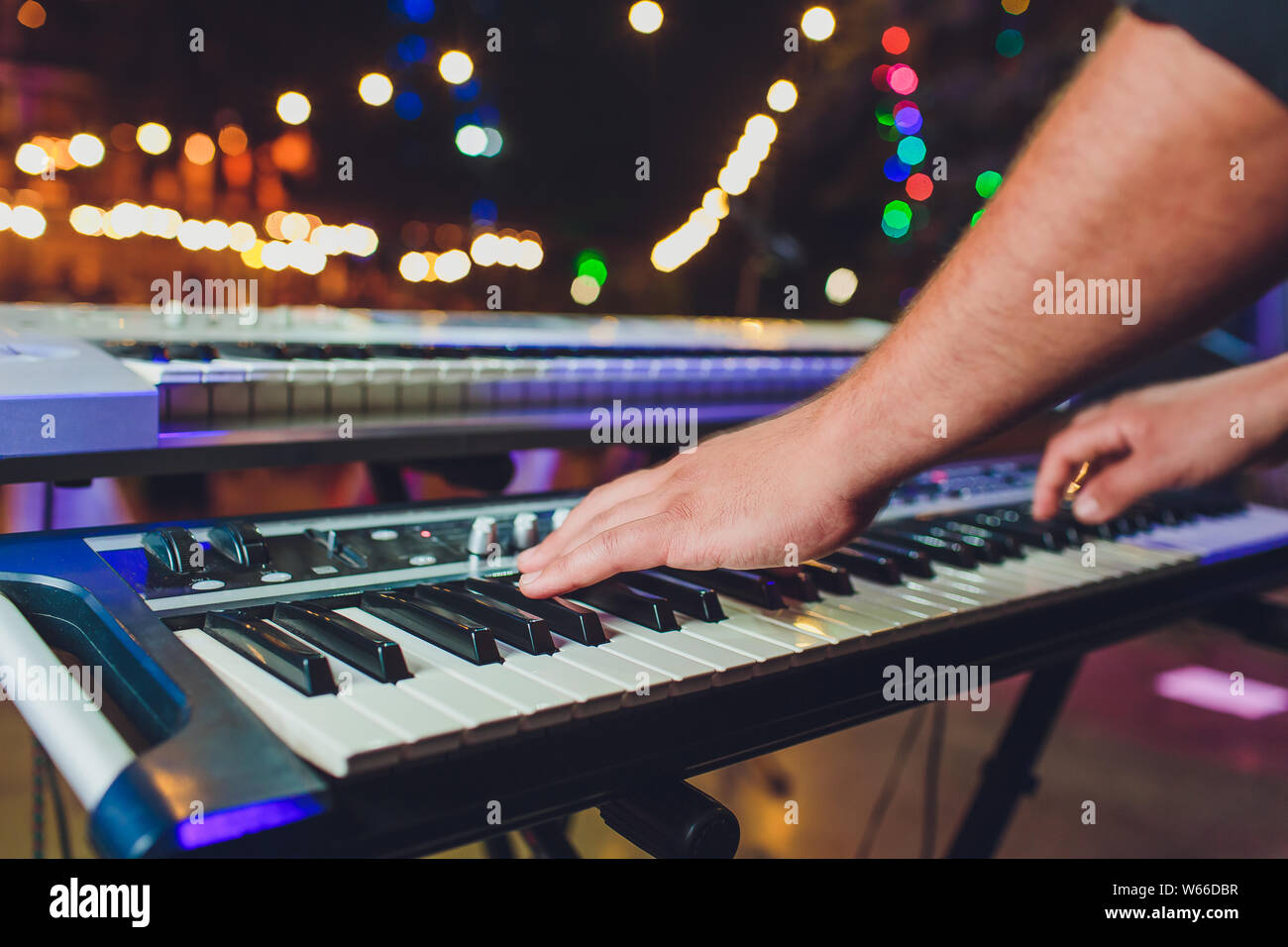Man playing electronic musical keyboard synthesizer by hands on white ...