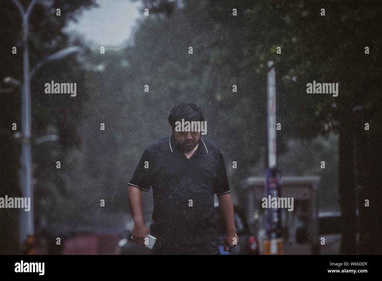 A pedestrian braves heavy downpour caused by Typhoon Ampil, the tenth ...