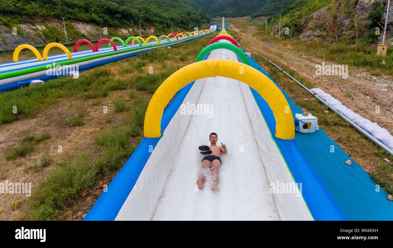 A tourist plays on Asia's longest water slide at Jingzhihu Resort in ...