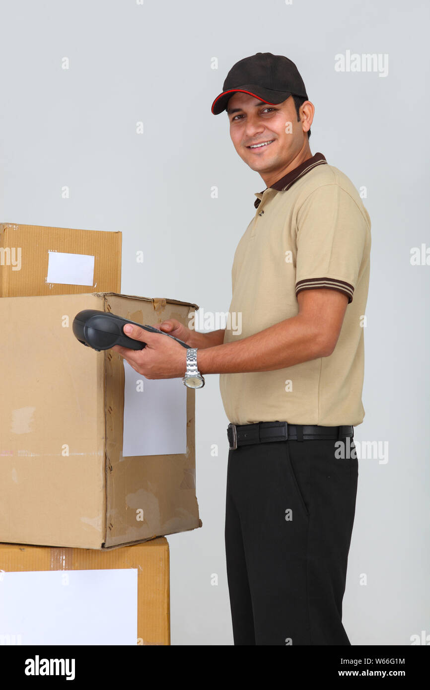 Delivery man standing with parcels and holding card reader Stock Photo ...
