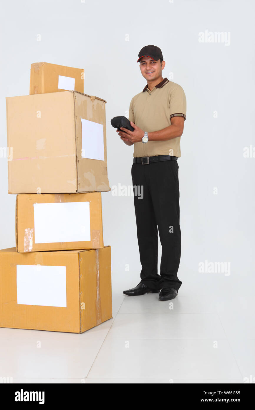 Delivery man standing with parcels and holding card reader Stock Photo ...