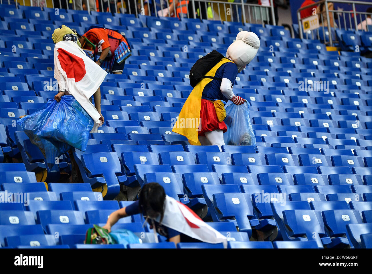 Heartbroken Japanese fans clean the stadium's stand after Japan was ...