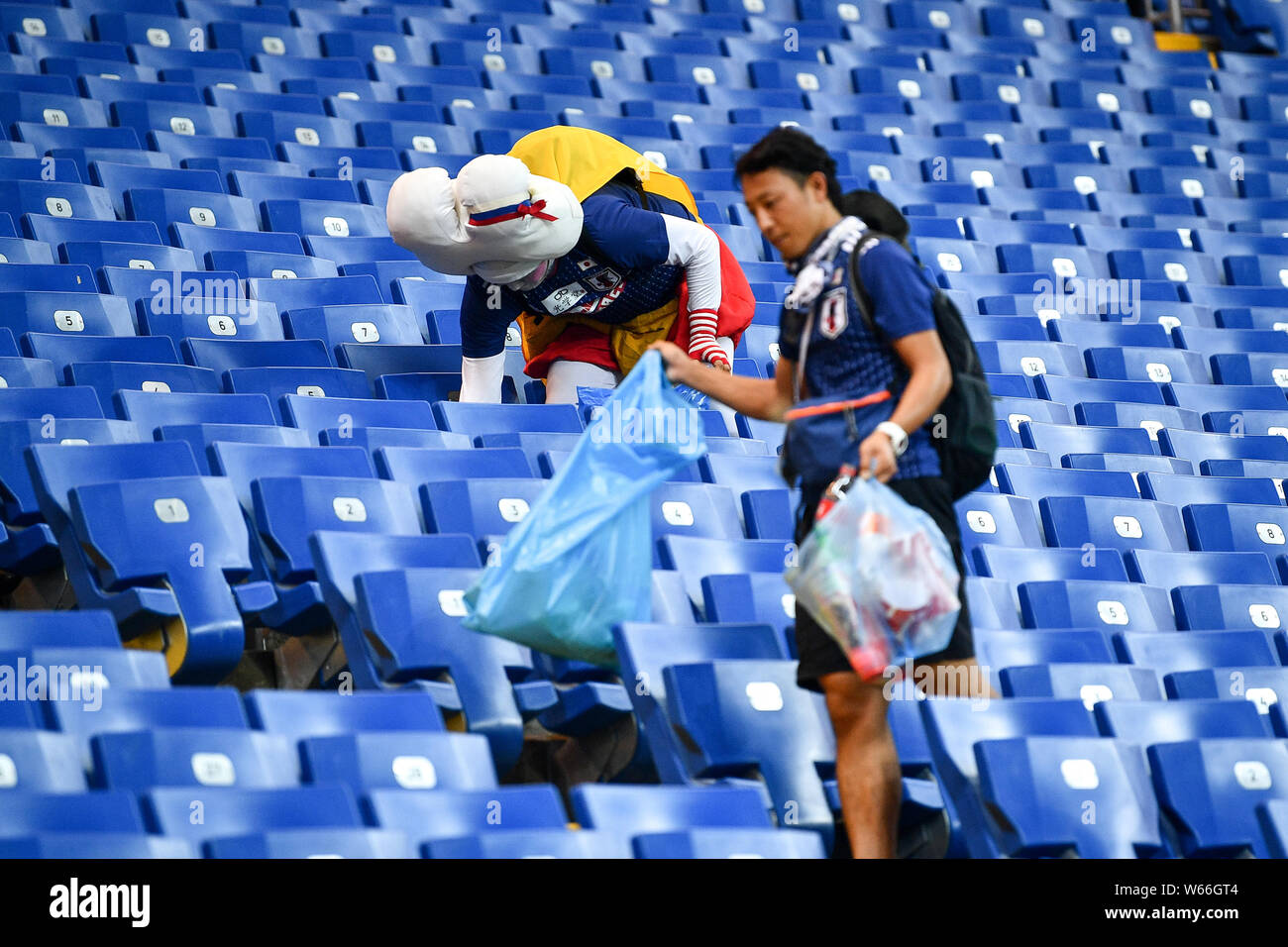 Heartbroken Japanese fans clean the stadium's stand after Japan was ...