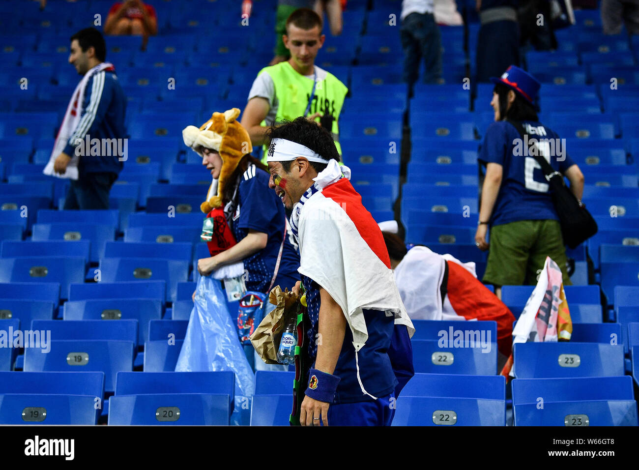 Heartbroken Japanese fans clean the stadium's stand after Japan was ...