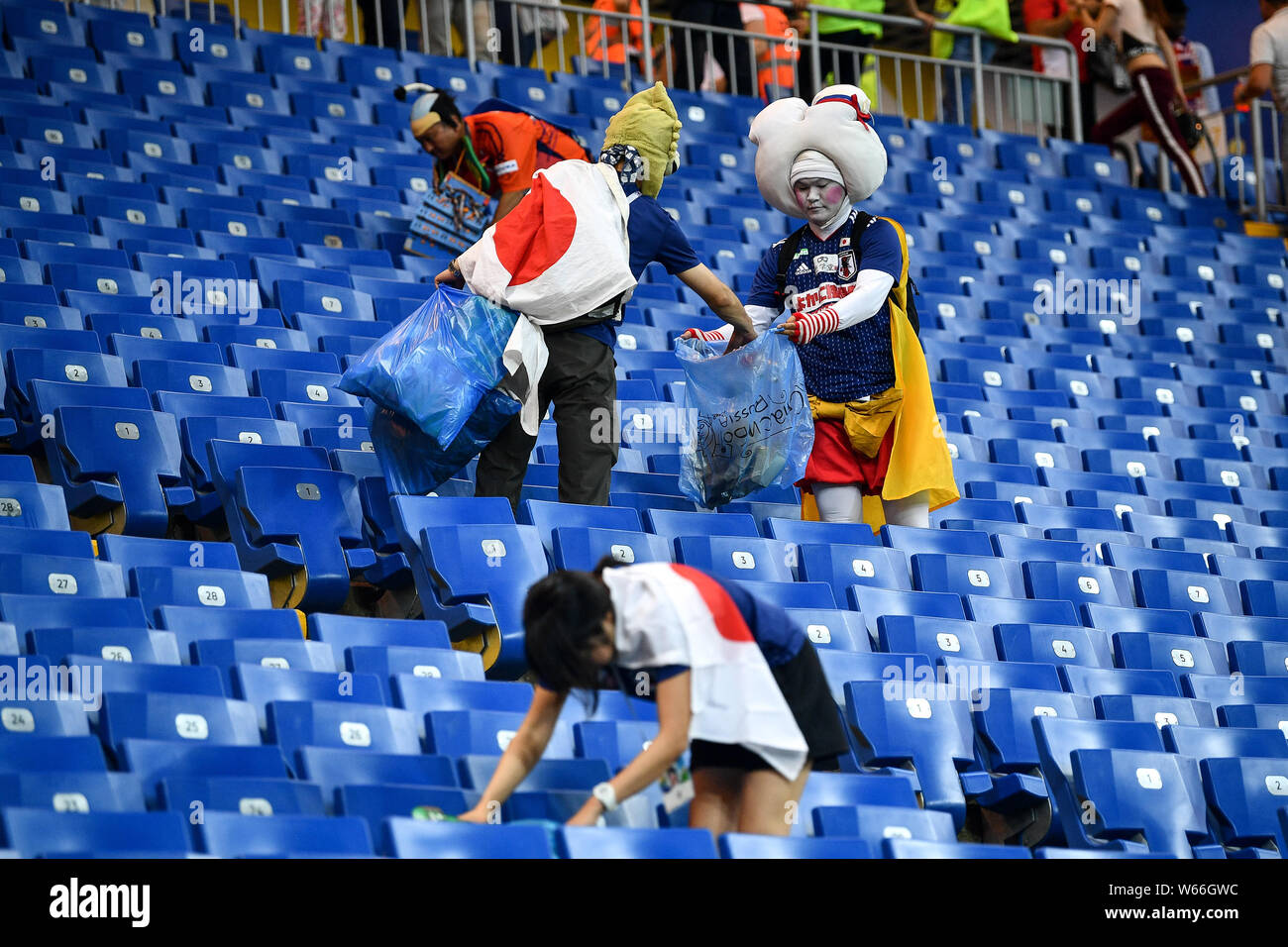 Heartbroken Japanese fans clean the stadium's stand after Japan was ...