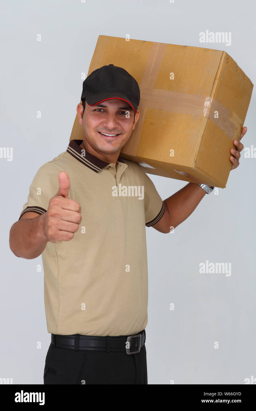 Delivery man carrying parcel and showing thumbs up sign Stock Photo - Alamy