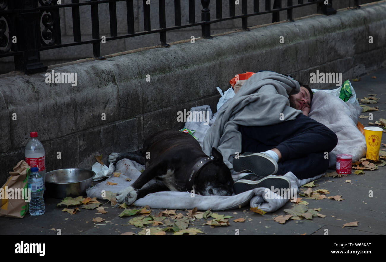 Homeless man and his dog sleep on the pavement near Trafalgar Square in ...