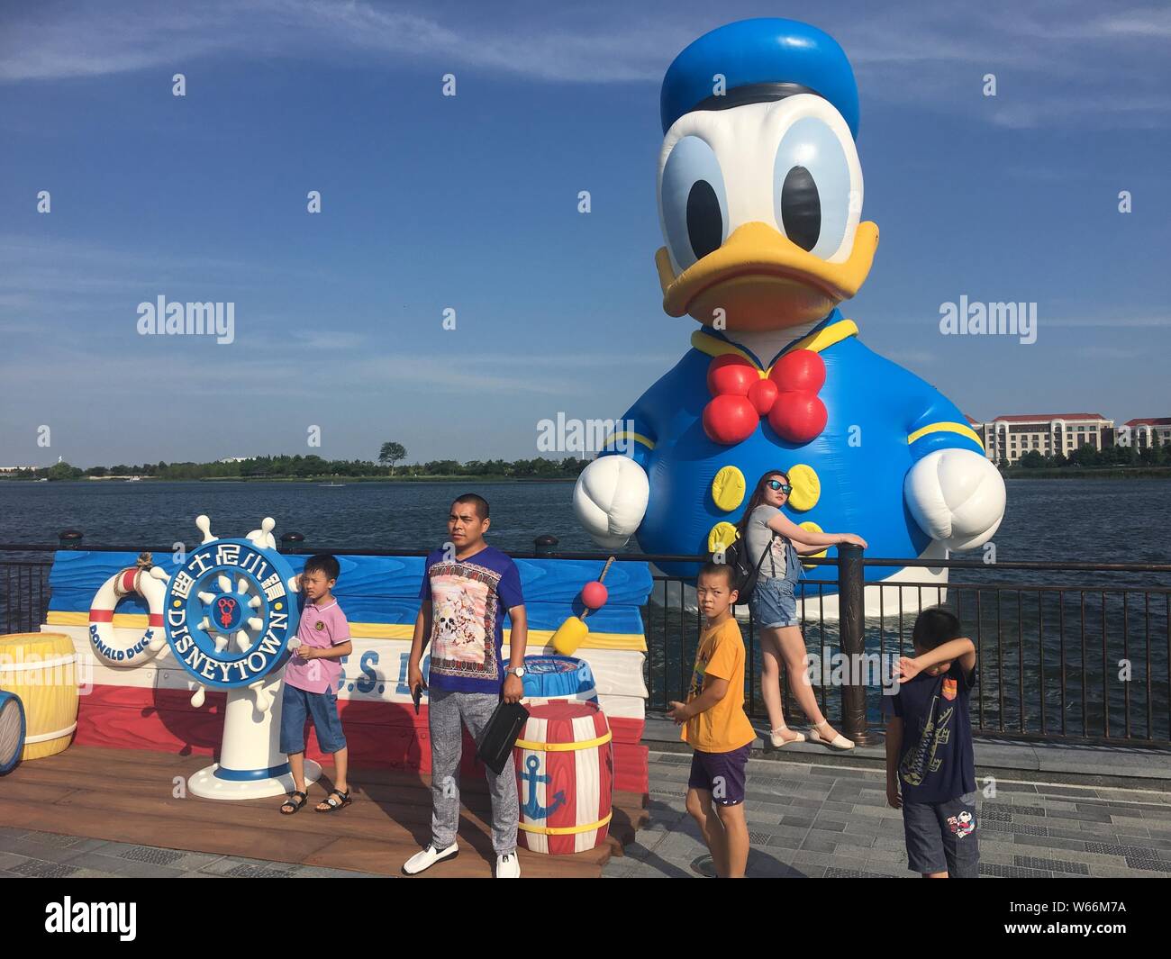 Tourists pose for photos with an 11-meter-tall inflatable Donald Duck ...