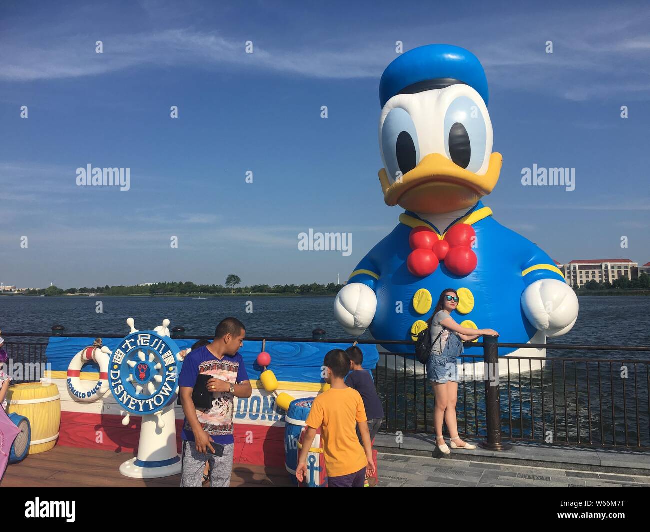 Tourists pose for photos with an 11-meter-tall inflatable Donald Duck ...