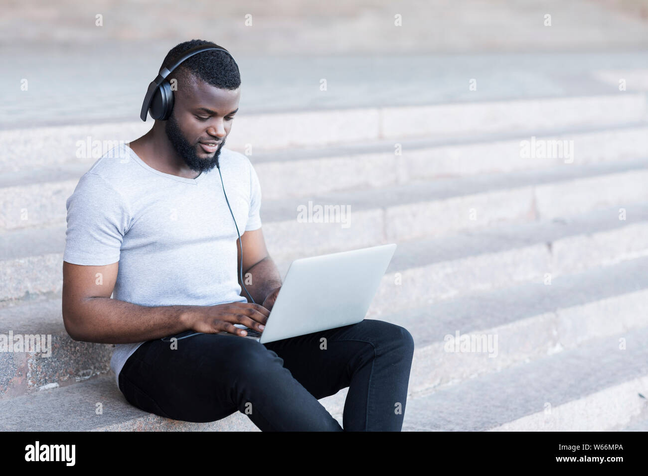 Young bearded african guy in headphones coding on laptop Stock Photo ...