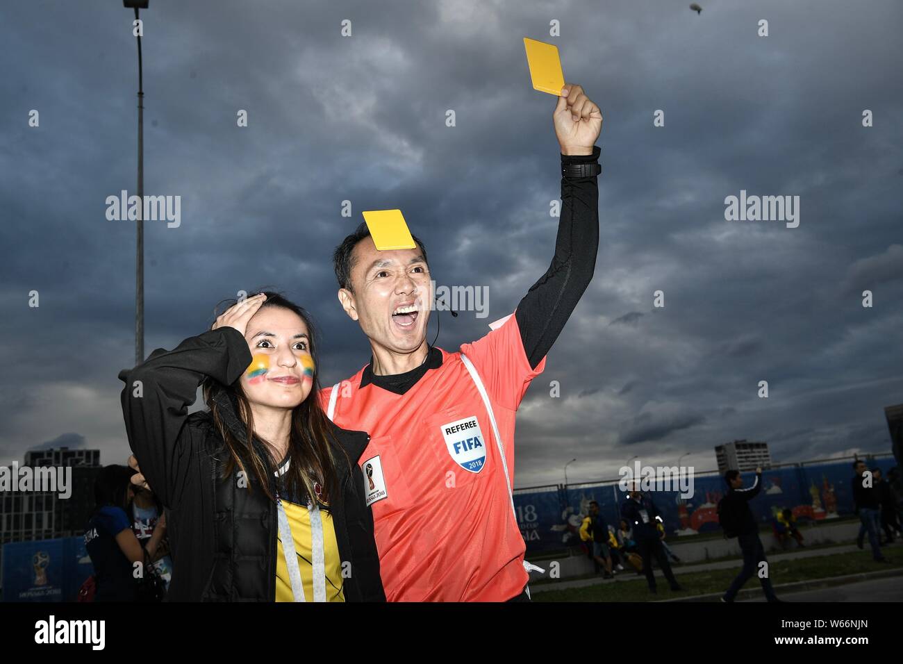 A Japanese fan who cosplays a referee holding up a yellow card poses ...