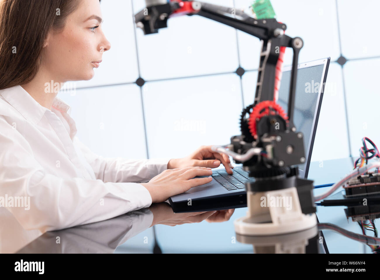 A young woman writes an algorithm for the robot arm. Science Research ...