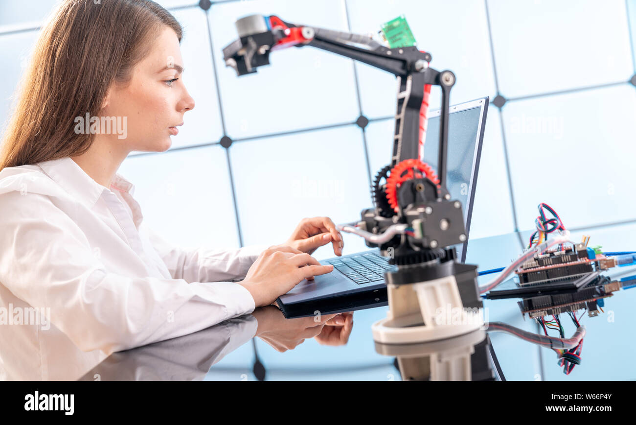 A young woman writes an algorithm for the robot arm. Science Research ...