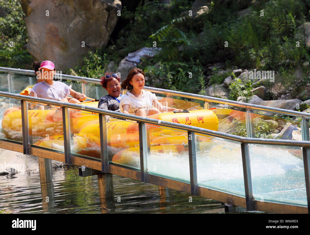 Tourists have fun on the 2.3-kilometer-long glass-bottomed waterslide ...