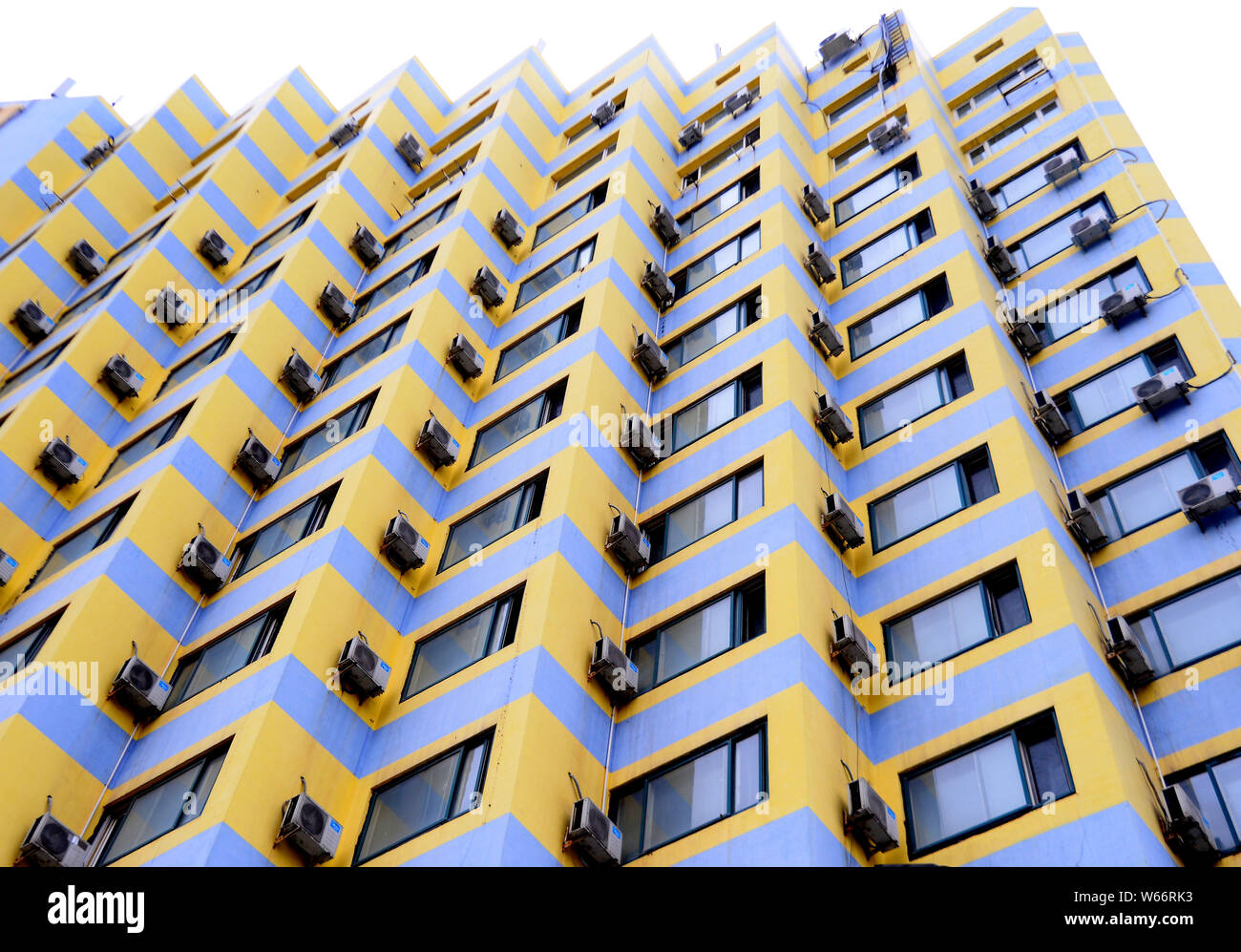 A striped building in yellow and blue is decorated with dozens of air ...