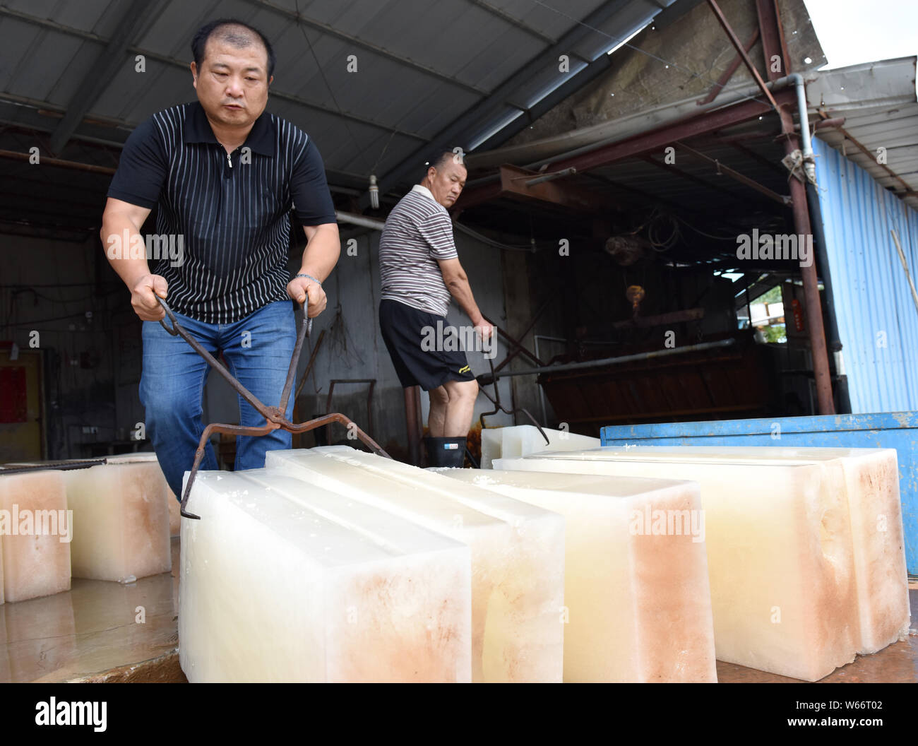 Chinese workers process ice blocks in an ice factory in Chaohu city ...