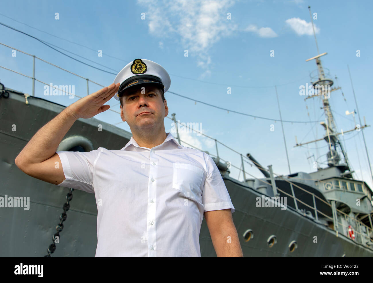 Navy officer standing beside warship and do salute.The captain in white ...