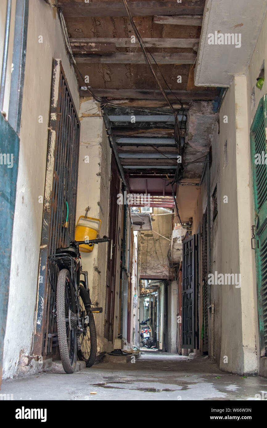 A narrow alley between the houses with the bike lean on the wall, Hanoi ...
