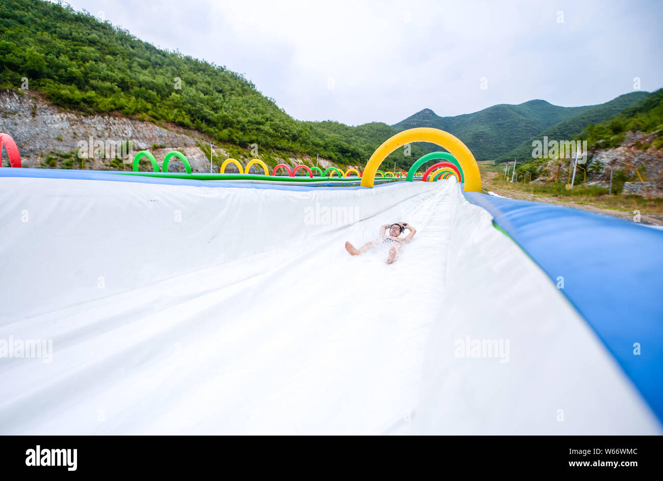 A tourist plays on Asia's longest water slide at Jingzhihu Resort in ...