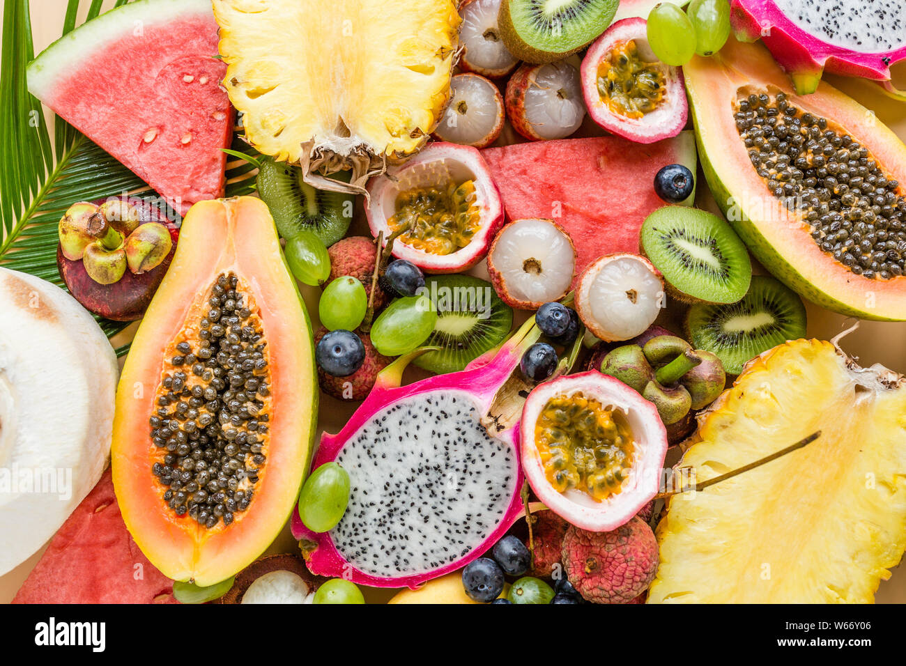 Fresh exotic fruits and tropical palm leaves on pastel orange ...
